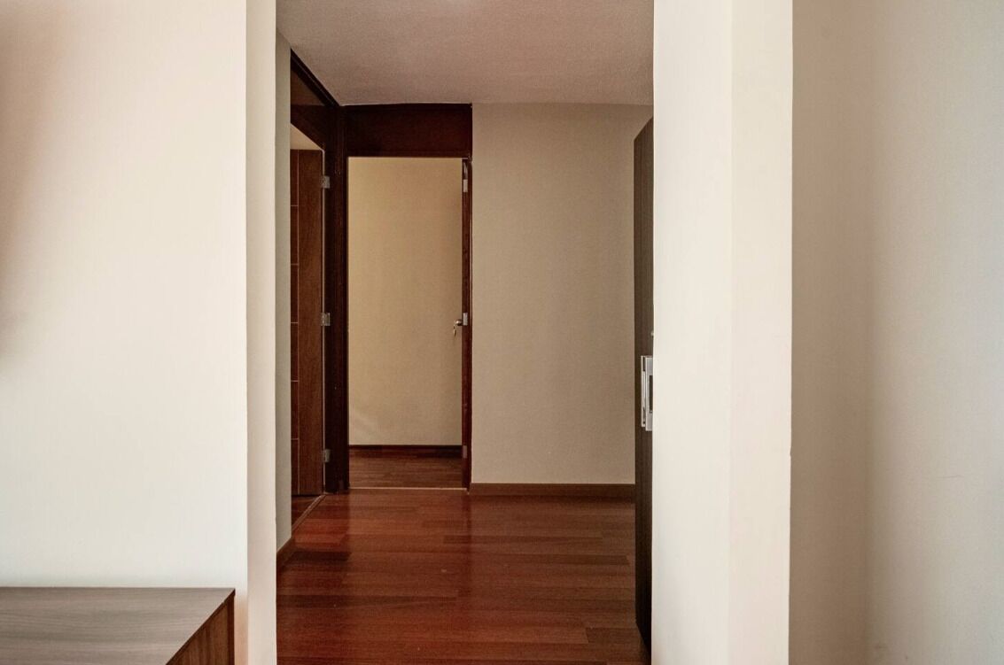 Corredor com piso de madeira e porta fechada no final.