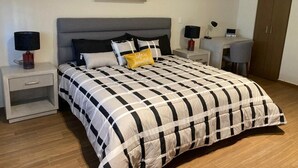 Quarto com cama, mesas de cabeceira, guarda-roupa e um quadro na parede.