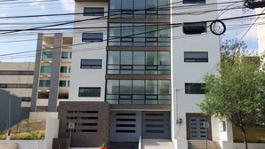 Um edifício moderno de vários andares com grandes janelas e telhado plano.