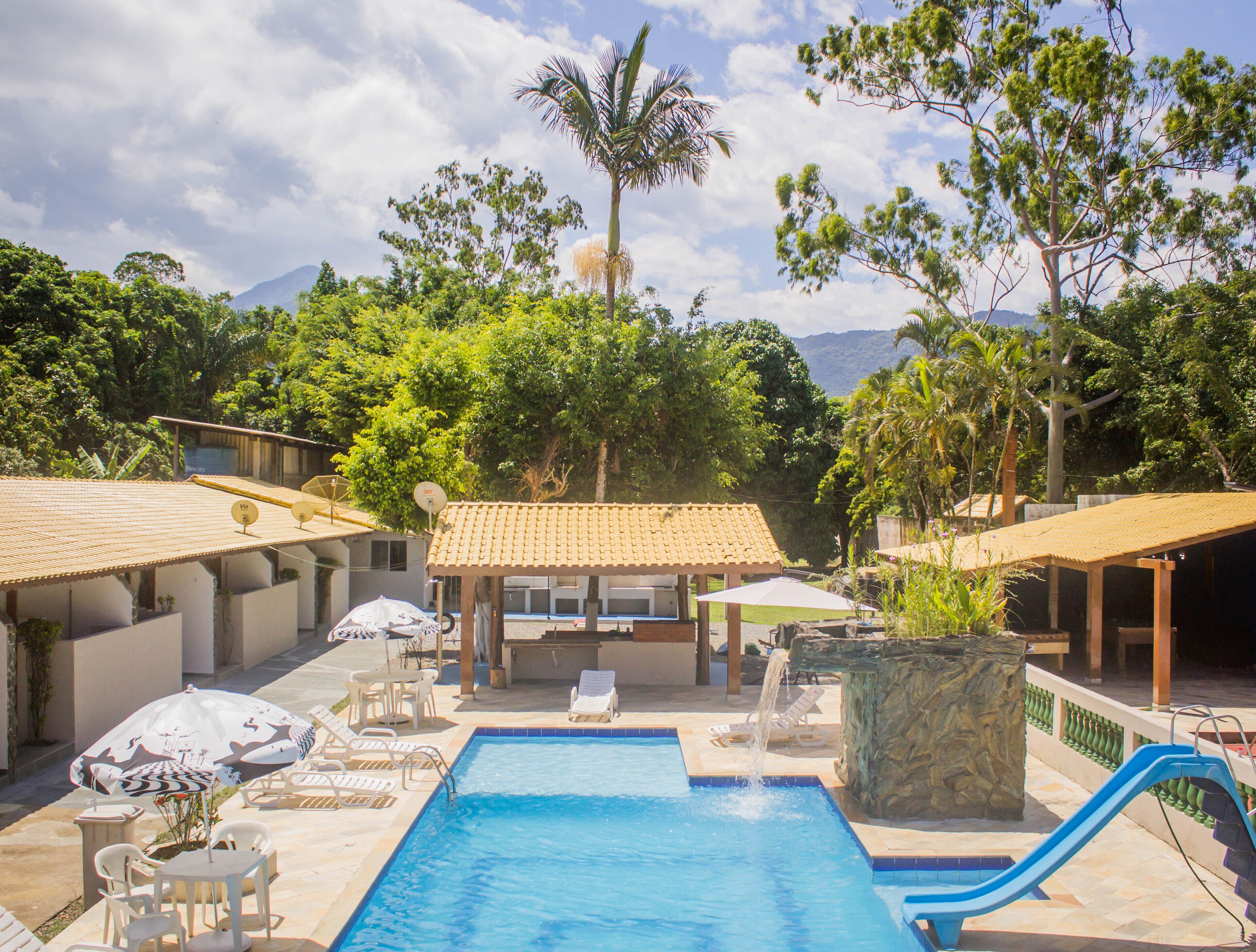 Piscina com escorregador, espreguiçadeiras e guarda-sóis.