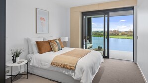 Quarto com uma cama grande, vista para uma piscina e porta de vidro que se abre para uma área externa.
