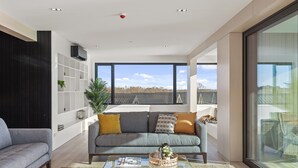 Uma sala de estar moderna com um sofá cinza, uma mesa de centro e uma estante.