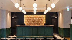 Uma área de recepção com balcão de check-in, parede de tijolos e chão quadriculado em preto e branco.