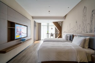 Quarto de hotel moderno com uma cama grande, uma televisão fixada na parede e uma escadaria para uma área externa.