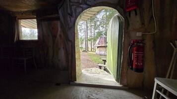 Interior rústico de madeira com uma porta que dá para o exterior, um extintor de incêndio na parede e um banco.