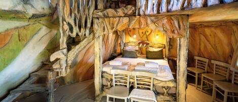 Um quarto rústico com uma cama, duas cadeiras e uma escada de madeira.
