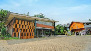 Um edifício moderno com fachada quadriculada, uma área externa coberta e uma escadaria que leva a um segundo andar.