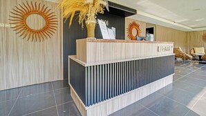 Uma receção com design moderno, com acabamento em madeira e um motivo decorativo de sol na parede.