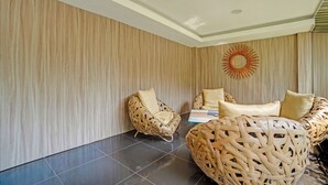 Um quarto com parede de madeira, duas cadeiras de palha, uma decoração de sol redonda e piso de azulejos.