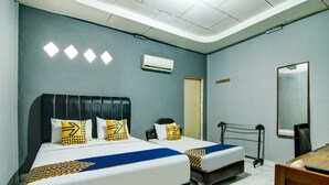 Quarto de hotel com duas camas, uma escrivaninha e um espelho.