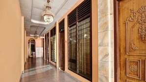 Um corredor com piso de azulejos, portas de madeira com detalhes entalhados e um lustre.