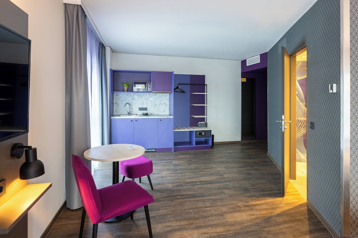 Quarto de hotel moderno com cozinha, mesa de jantar e cadeiras, e um closet espaçoso.