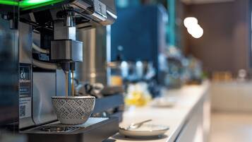 Uma máquina de café com uma xícara e pires, um prato e uma colher em uma bancada.