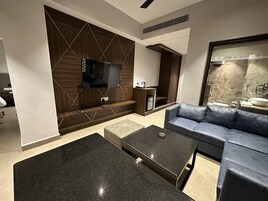 Uma sala de estar moderna com uma TV de tela plana fixada em uma parede de madeira, um sofá cinza e uma mesa de centro.