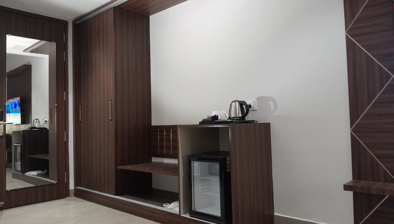 Quarto com guarda-roupa, mini-frigorífico e espelho.