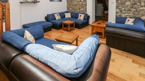 Uma sala de estar com sofá seccional, mesa de centro e televisão na parede.