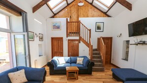 Uma sala de estar espaçosa com escada de madeira, um sofá azul e uma mesa de centro de madeira.