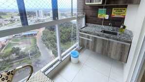 Varanda com vista para a paisagem urbana, micro-ondas e pia com uma embalagem de sabonete.