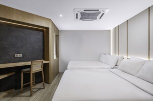 Quarto moderno com escrivaninha de madeira, uma cadeira, cama com roupa de cama branca e um respiradouro no teto.