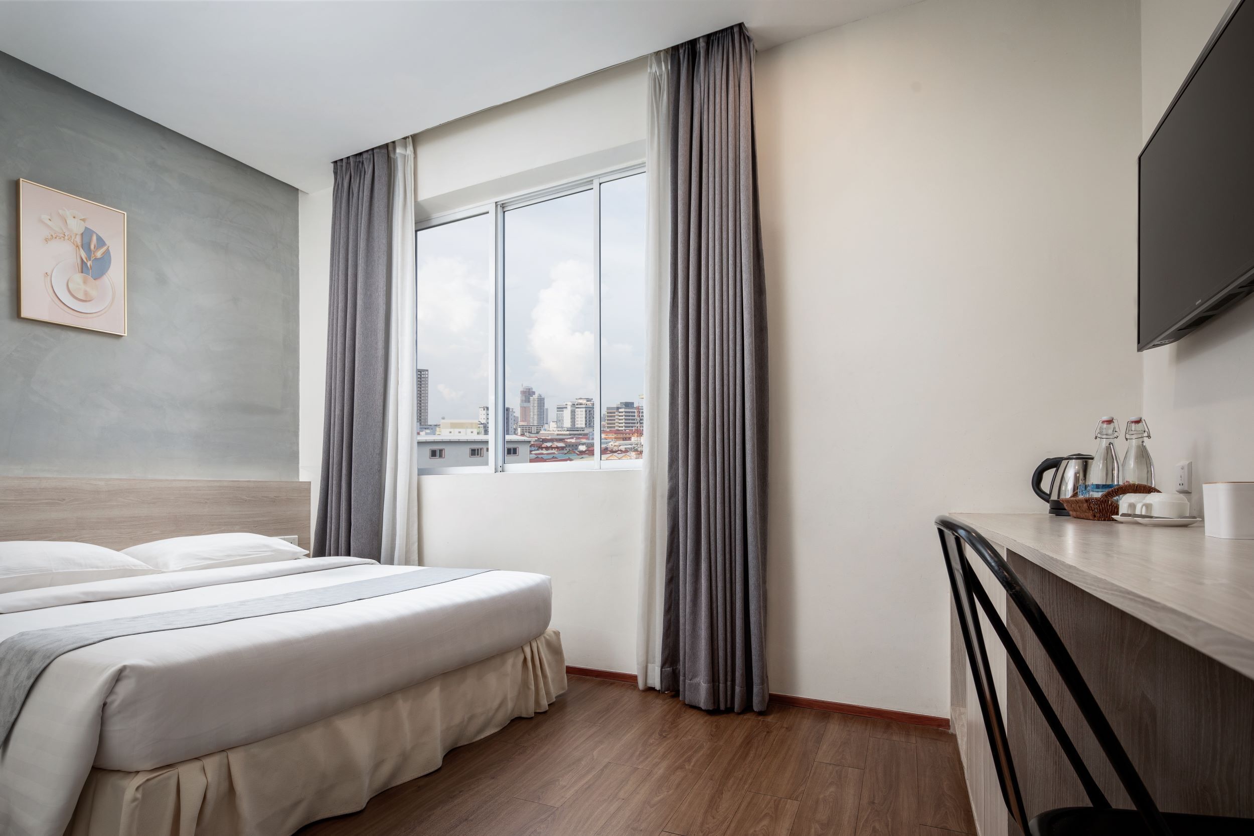Quarto de hotel com cama grande, vista para a cidade, TV de tela plana e cozinha compacta.