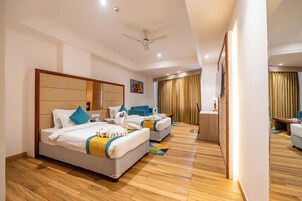 Quarto de hotel com duas camas, um ventilador de teto e um espelho grande.