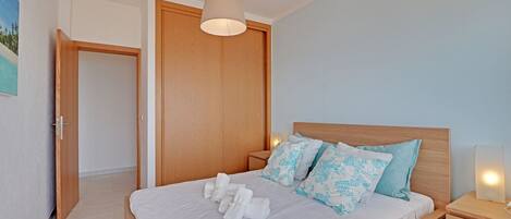 Quarto com cama, cabeceira de madeira e mesa de cabeceira com abajur.