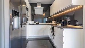 Cozinha moderna equipada com frigorífico embutido, micro-ondas e máquina de café.