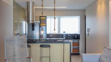 Uma cozinha moderna com uma ilha central, banquetas de bar e um lustre.