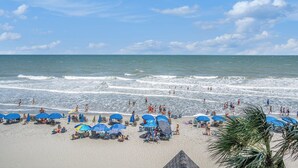 Uma praia com guarda-sóis e pessoas.