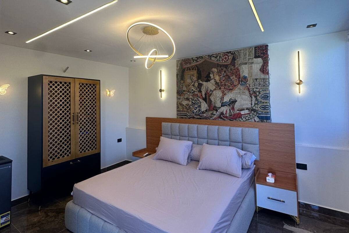 Quarto moderno com cama grande, guarda-roupa e um objeto decorativo na parede.