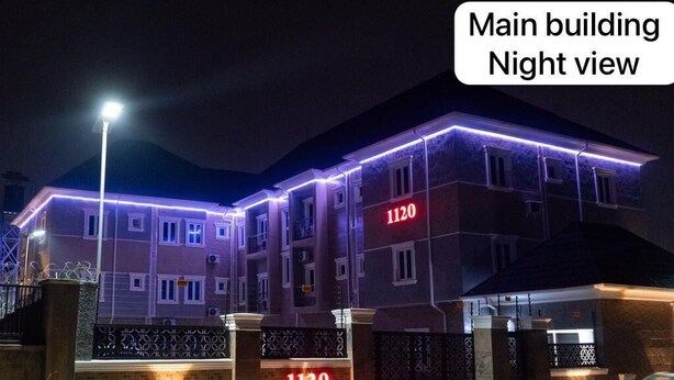 Um edifício com vários andares e uma placa de fachada bem visível com o número '1120', iluminada por luzes no chão.