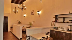Uma cozinha acolhedora com uma ilha central, um espaço de refeições com cadeiras e um micro-ondas na bancada.