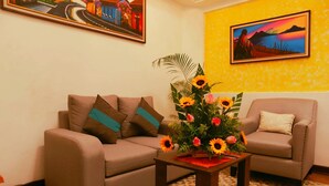 Uma sala de estar com sofá, poltrona e mesa de centro com um arranjo floral.