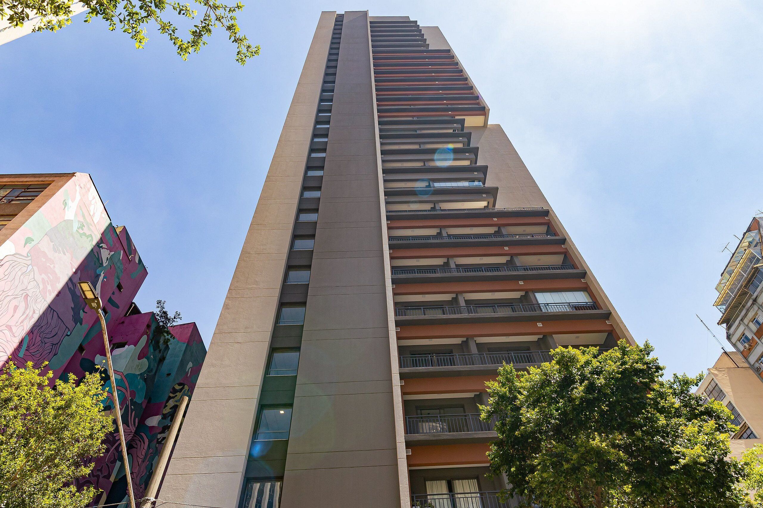 Um edifício alto e moderno, com várias varandas e céu claro.