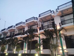 Um hotel com vários andares, varandas, aparelhos de ar condicionado e fachada bem iluminada.