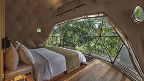 Quarto com uma grande janela, uma cama e piso de madeira.