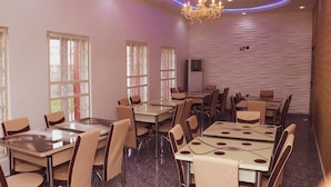 Uma área de refeições com várias mesas e cadeiras, um candelabro e paredes com padrão.