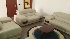 Uma sala de estar com um sofá bege, uma mesa de centro redonda e um tapete estampado.