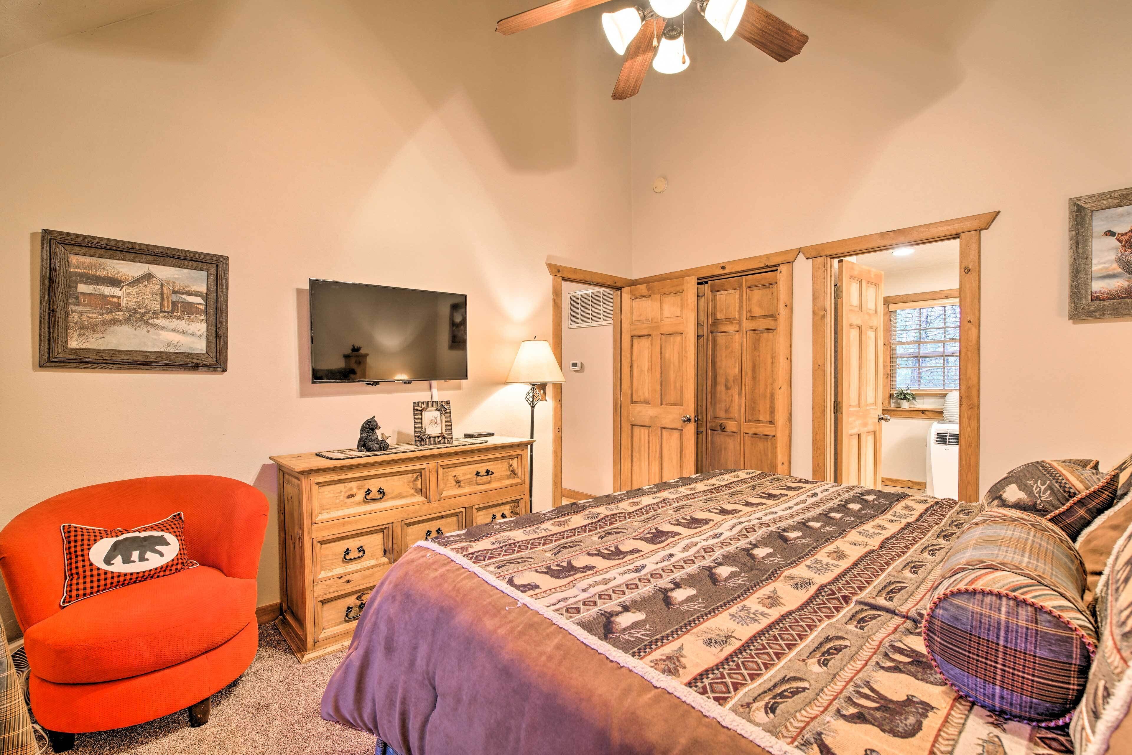 Quarto com cama, guarda-roupa de madeira, televisão, cadeira e cómoda.