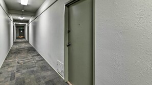 Um corredor com piso coberto por carpete, uma porta verde e um luminário no teto.