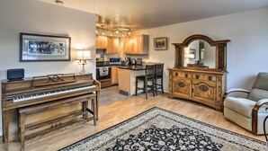 Ampla sala de estar com piano, mesa de jantar, sofá e um espelho grande.