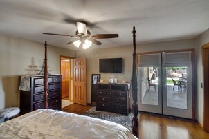 Quarto com cama de dossel, cómoda de madeira e ventoinha no teto.