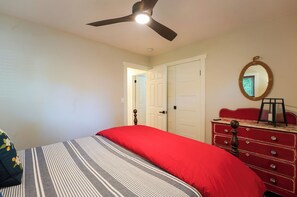 Quarto com cama, cômoda, espelho e ventilador de teto.