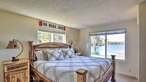 Quarto com cama grande, placa indicando 'NO WAKE ZONE', janela com vista para a água e abajur em uma mesa de cabeceira.