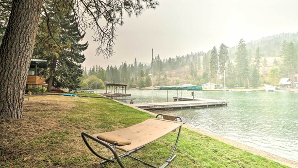 Vista para um lago com um deck de madeira, um banco e um gazebo.