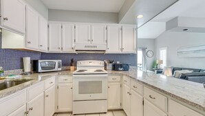 Uma cozinha moderna com armários brancos, forno embutido, micro-ondas e fogão a gás.
