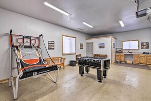 Uma cesta de basquete, uma mesa de futebol de mesa e um espaço de trabalho com computador e teclado.