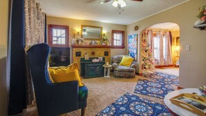 Uma sala de estar acolhedora com lareira, ventilador de teto e árvore de Natal.