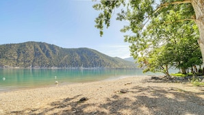 Uma praia com vista clara para um lago e colinas arborizadas ao fundo.