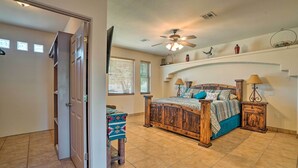 Quarto com cama de madeira, ventilador de teto e uma pequena mesa com luminárias.